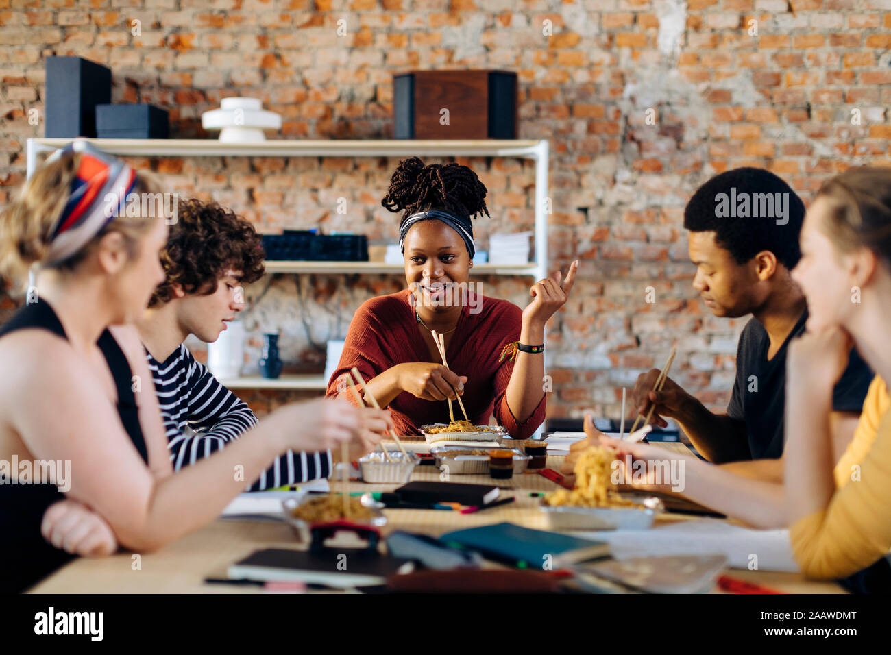 Young people sitting together at table having lunch break Stock Photo ...