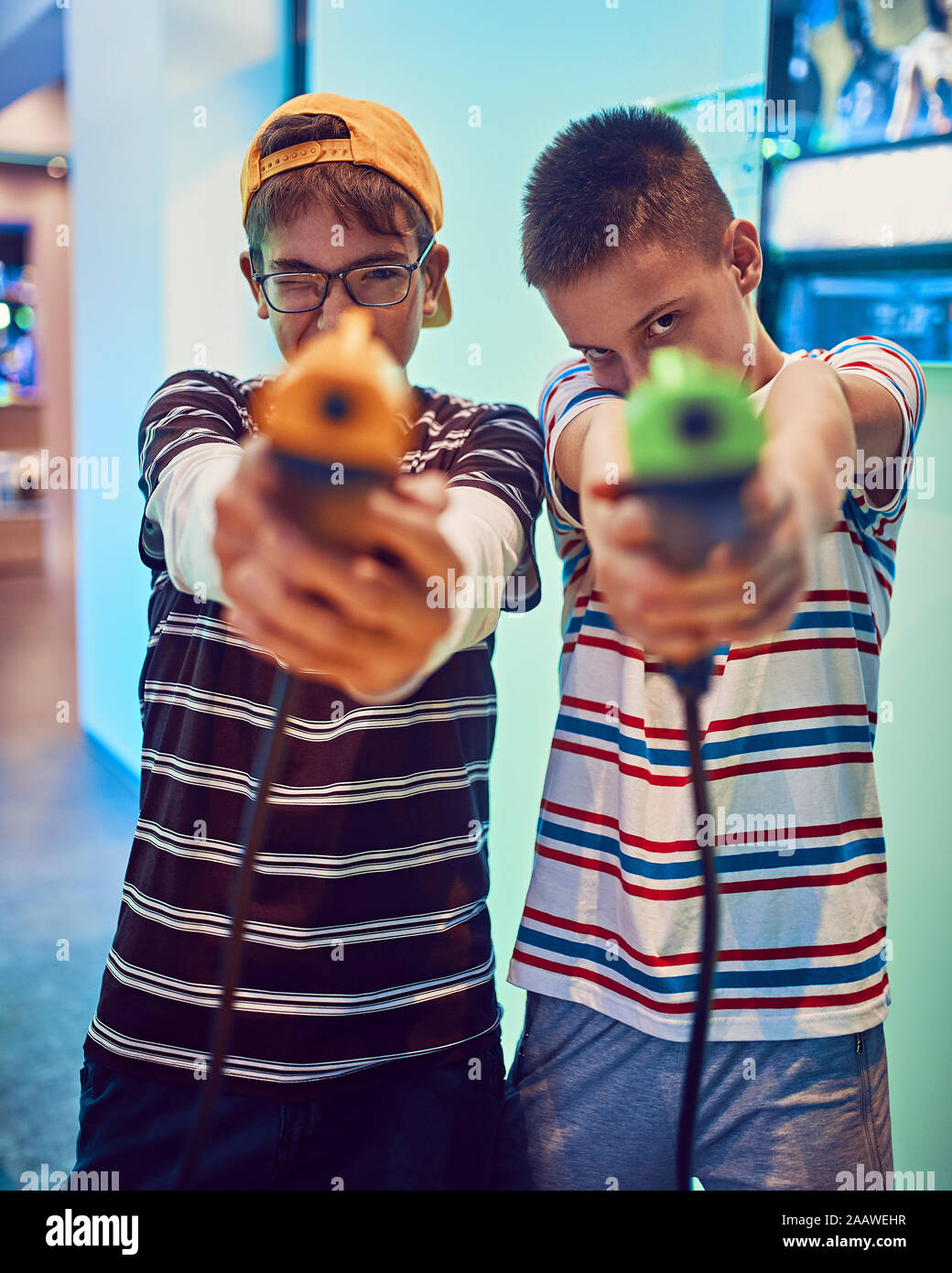 Portrait of teenage friends shooting with pistols in an amusement ...