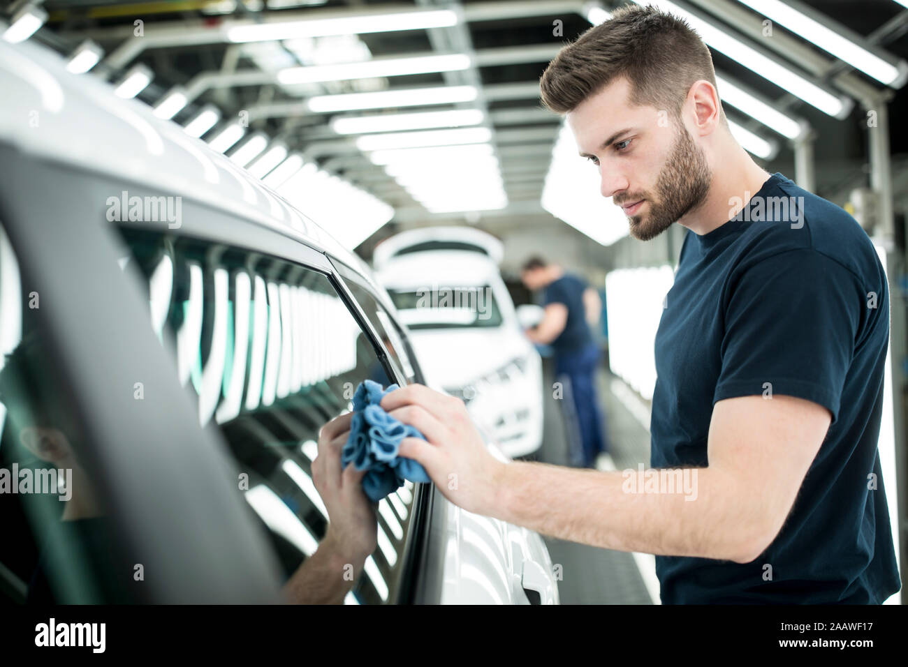 Man working in modern car factory wiping finished car Stock Photo - Alamy