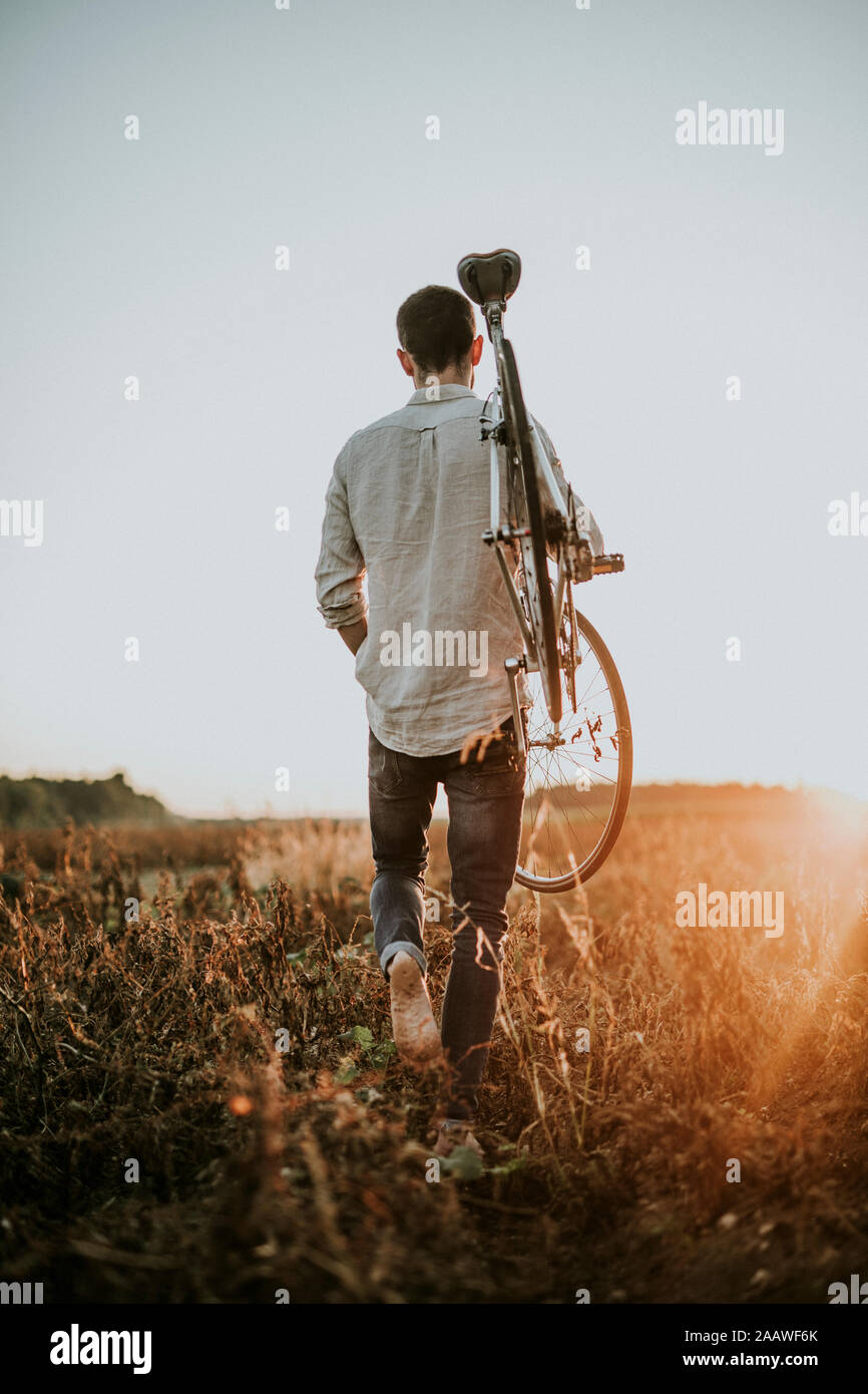 Rear view of a young man carrying a racing cycle in the sunshine Stock ...