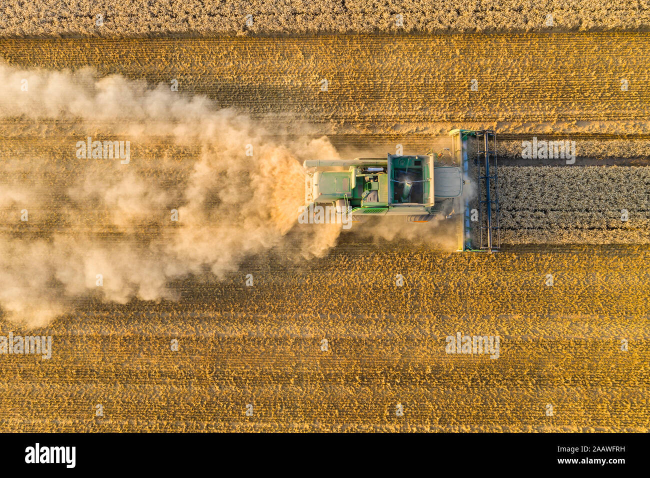 Aerial view of combine harvester on agricultural field during sunset ...