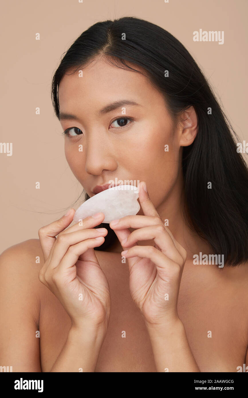 Portrait of young female Chinese woman using gua sha stone Stock Photo ...