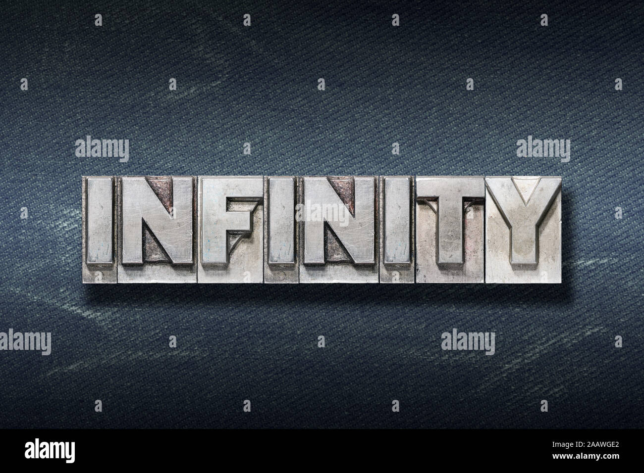 infinity word made from metallic letterpress on dark jeans background ...