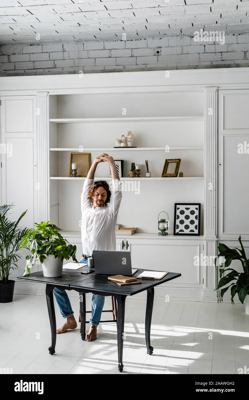 Man sitting desk laptop stretching hi-res stock photography and images ...