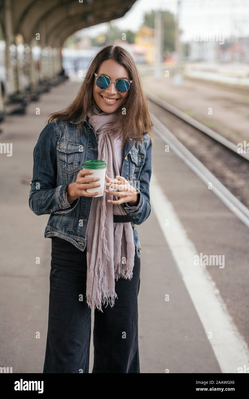 Young smiling traveller with coffee to go on train station Stock Photo ...