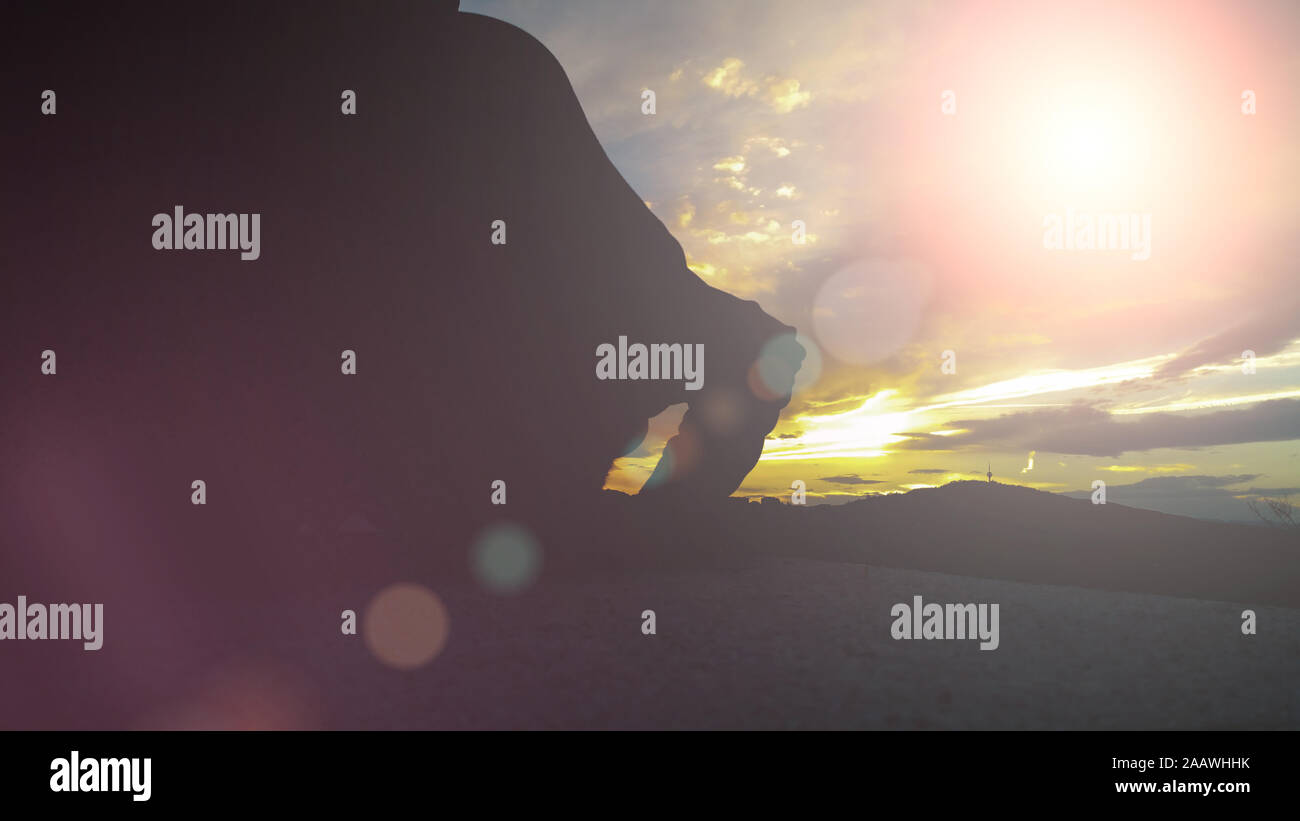 Silhouette of young muslim man praying outside during sunset with lens ...