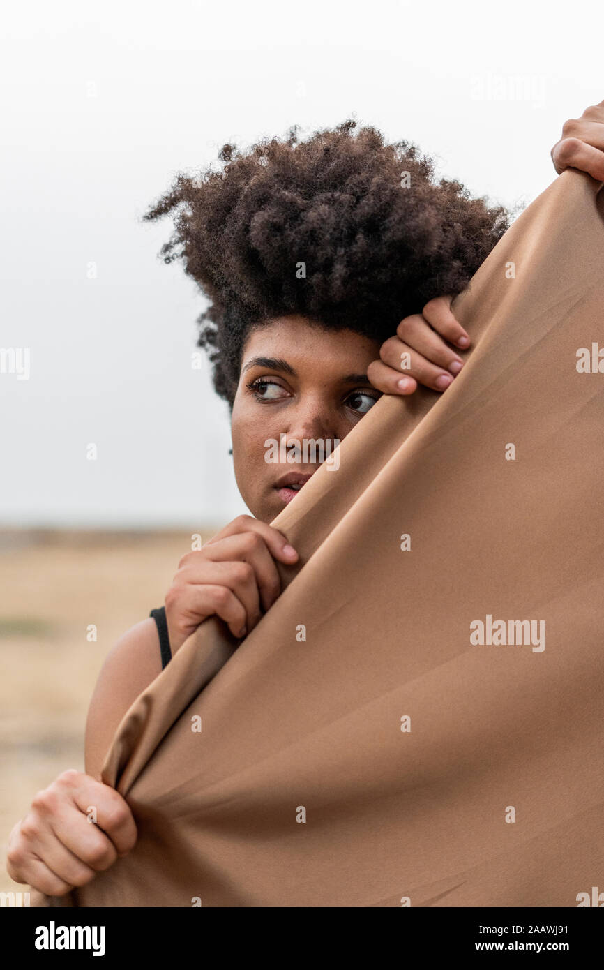Portrait of young woman behind cloth hold by four hands Stock Photo - Alamy