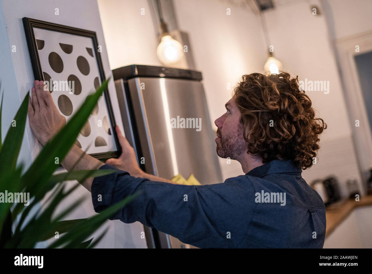 Man hanging up picture on the wall Stock Photo - Alamy