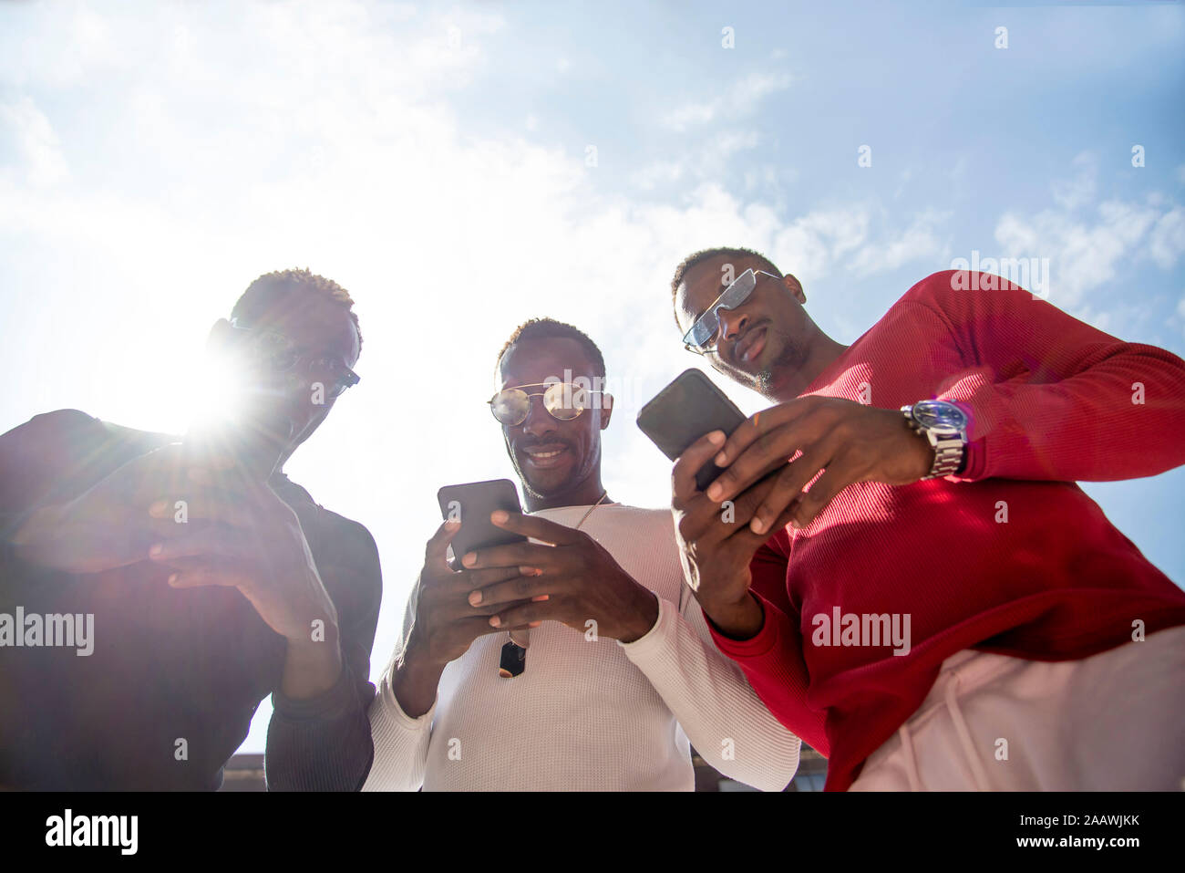 Three cool young men using cell phones in backlight Stock Photo - Alamy