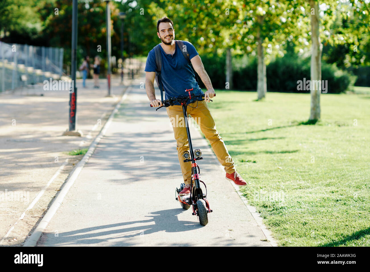 Portrait of smiling man riding electric scooter Stock Photo - Alamy