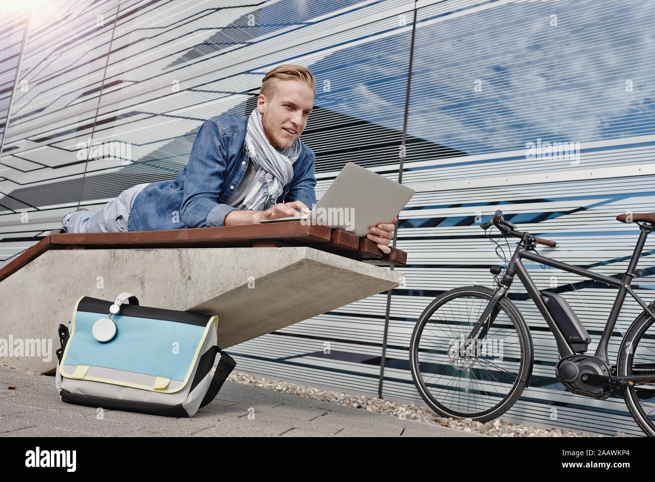 Student lying on bench and using laptop Stock Photo - Alamy