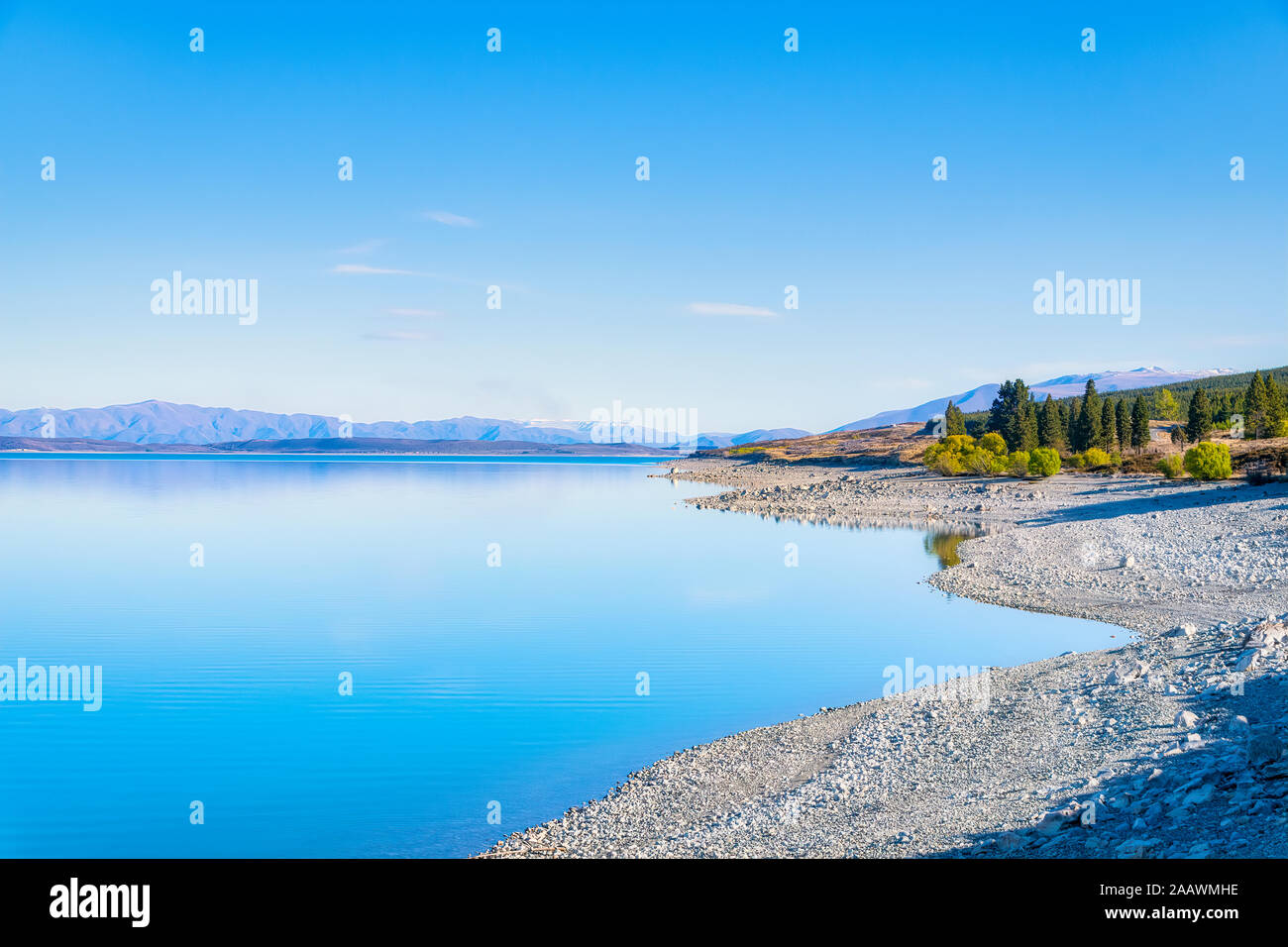 New Zealand, South Island, Clear sky over rocky shore of Lake Pukaki ...