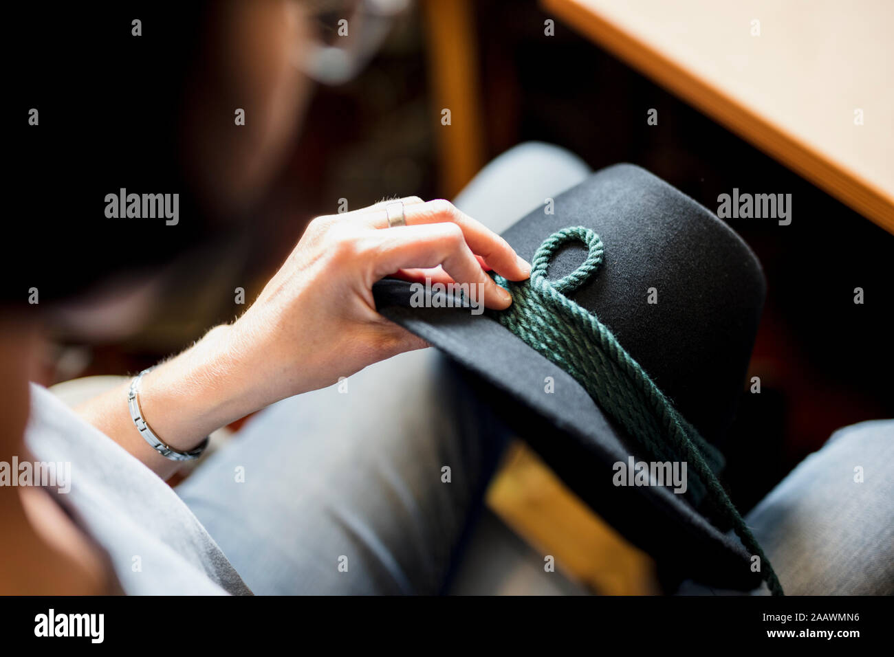 Midsection of woman rolling rope on hat while sitting in workshop Stock ...