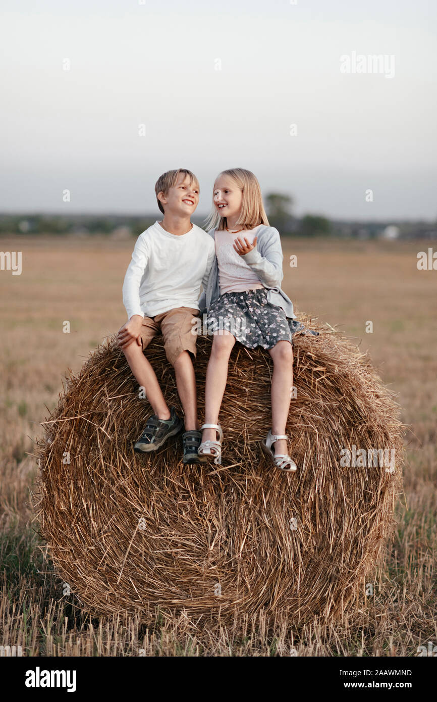 Two kids sitting on the haystack Stock Photo - Alamy