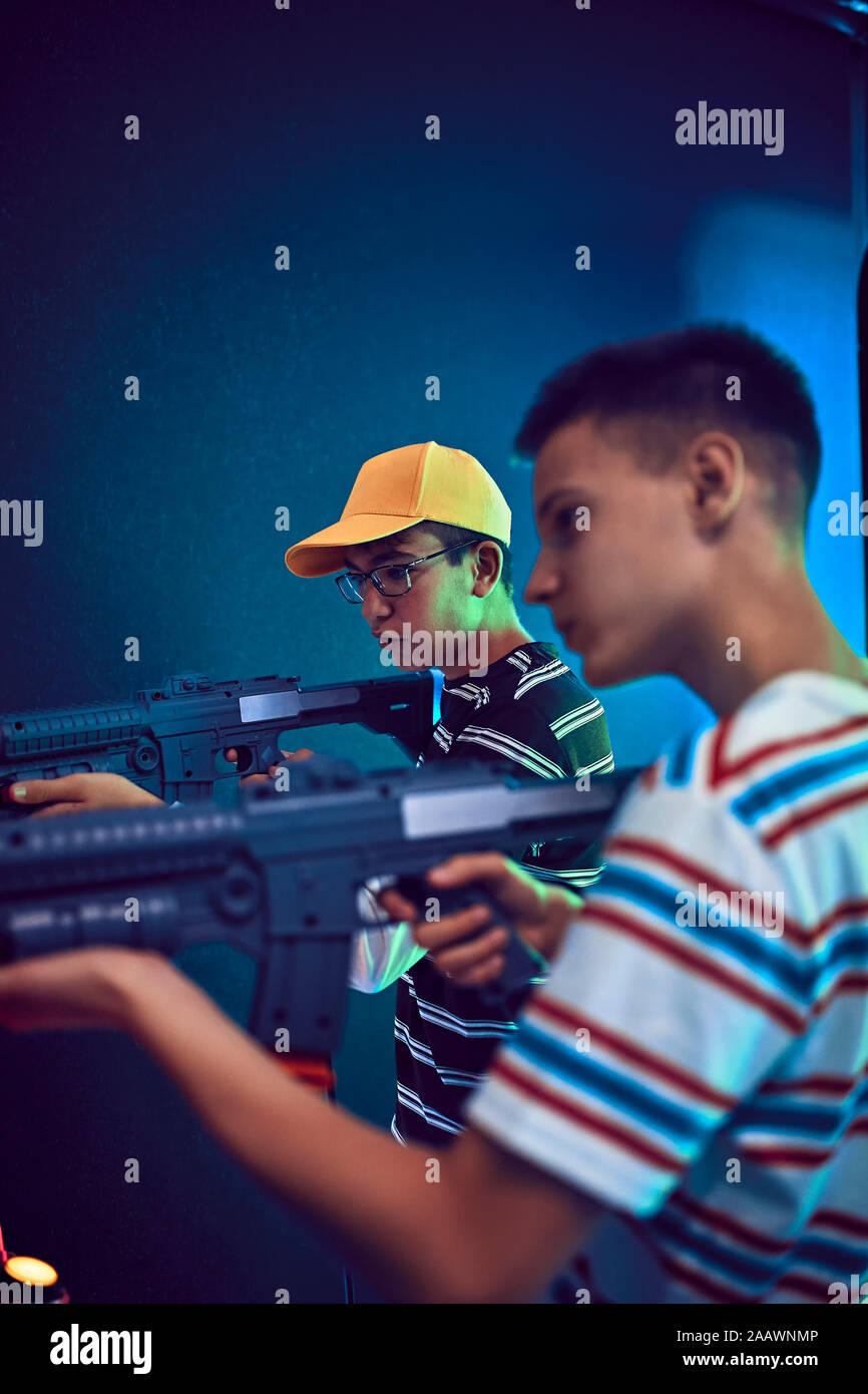 Teenage friends shooting with guns in an amusement arcade Stock Photo ...