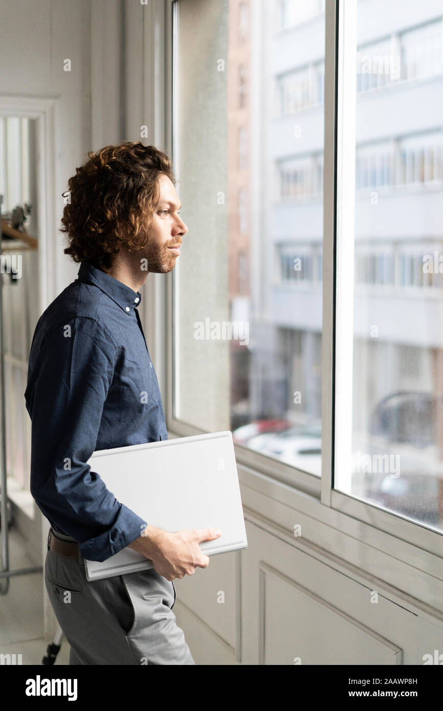 Man holding folder in a studio looking out of window Stock Photo - Alamy