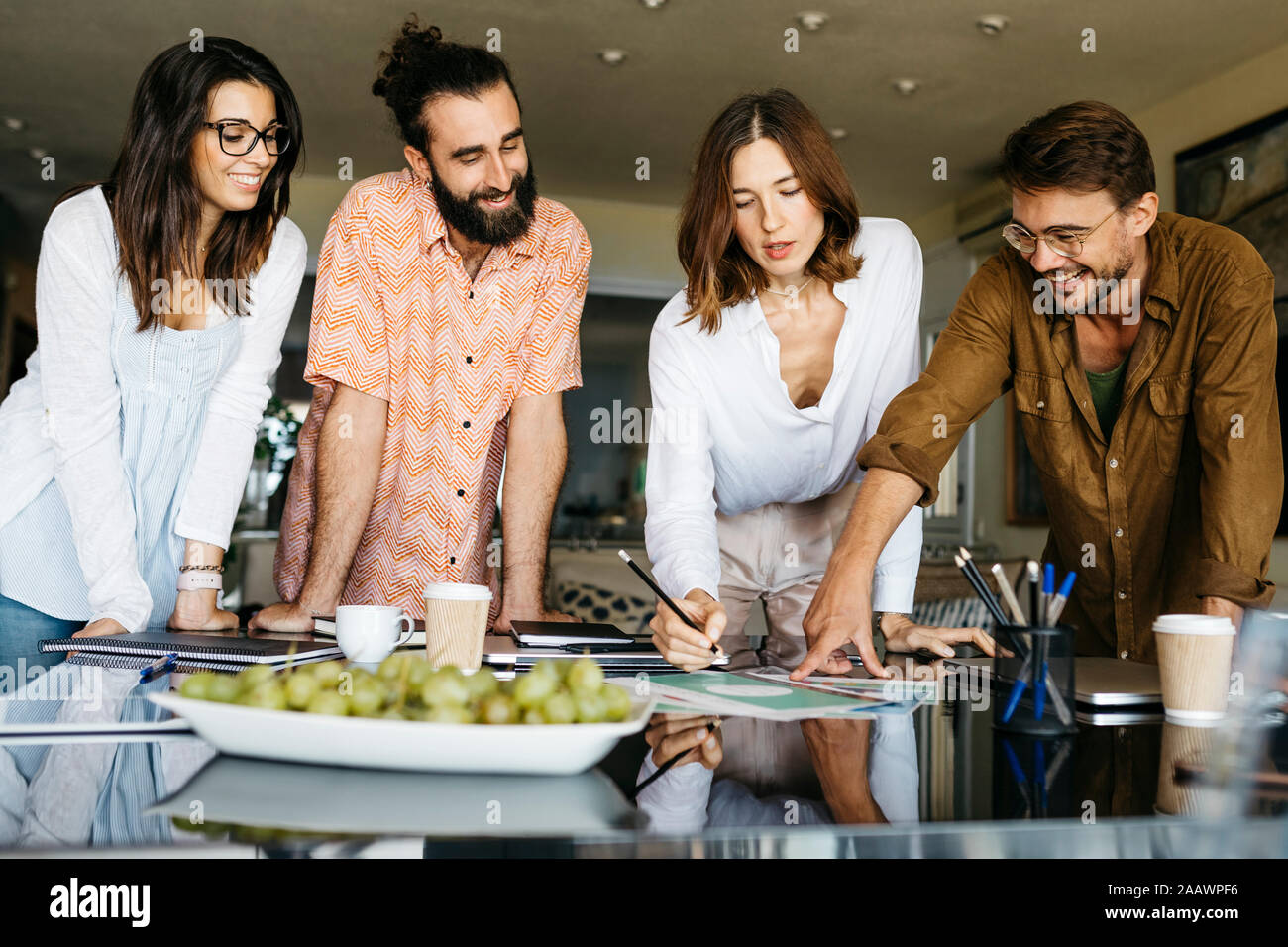 Happy friends working together on table at home Stock Photo - Alamy