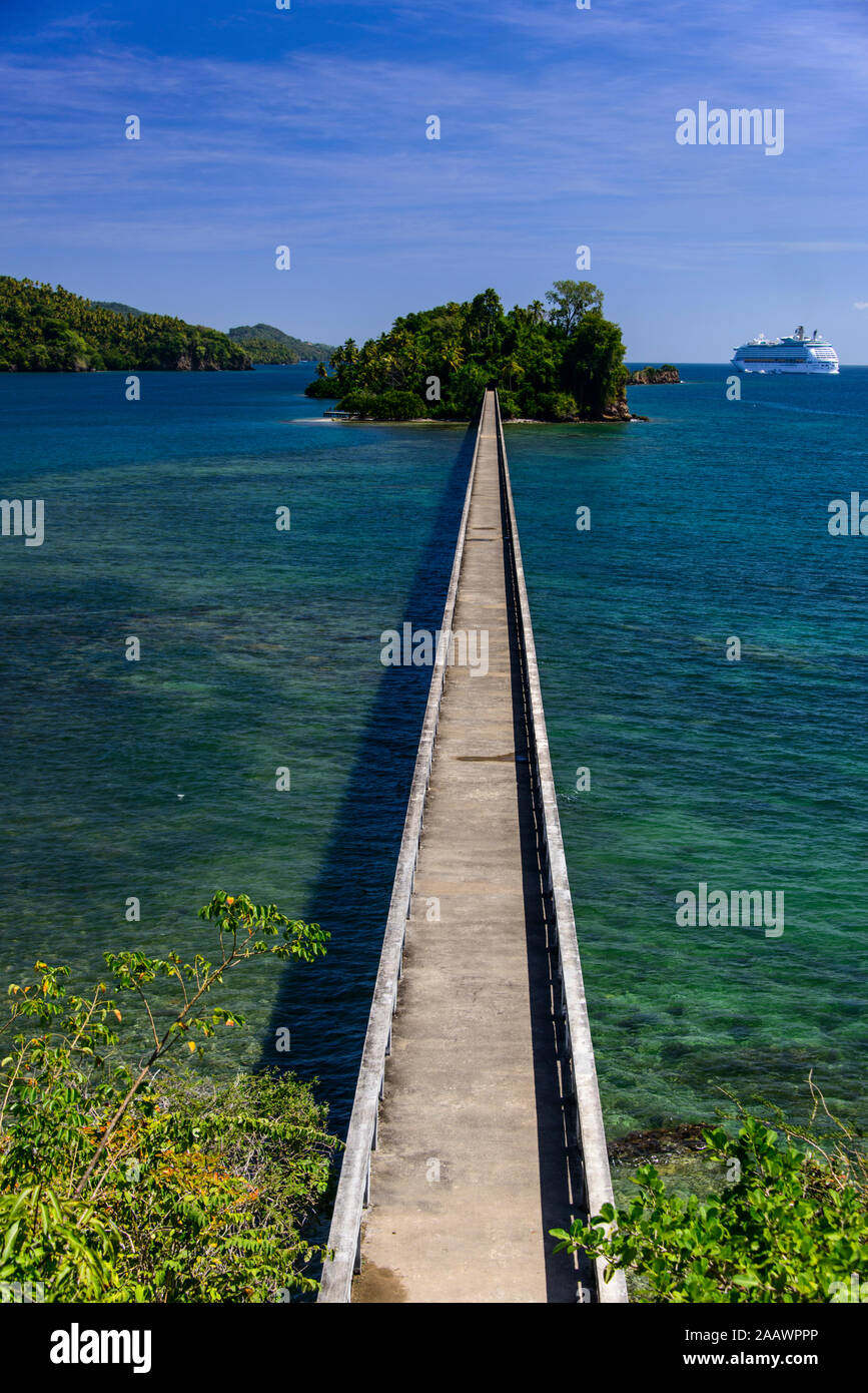 High angle view of empty footbridge leading towards island against blue ...