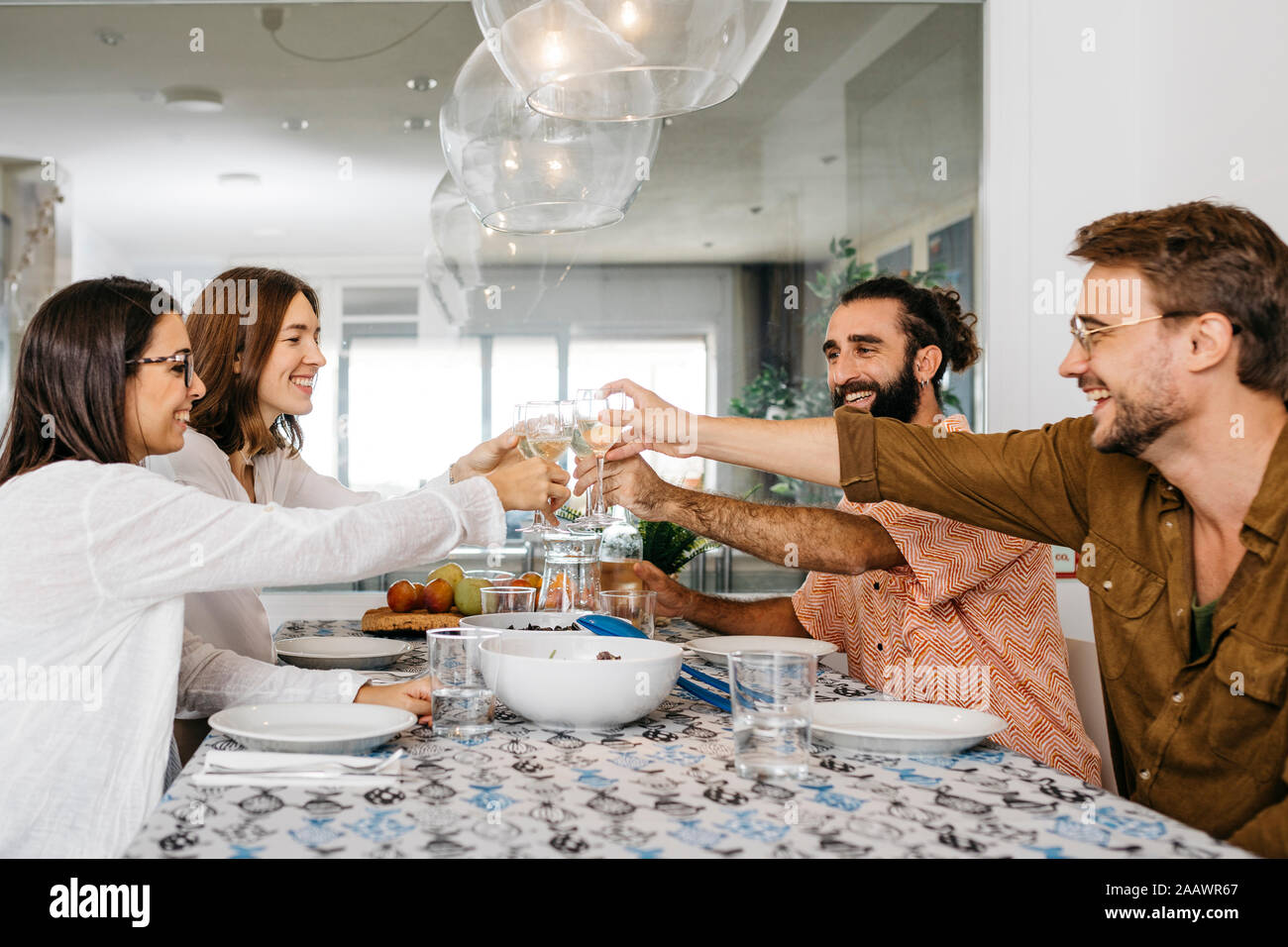 Happy friends having lunch together clinking glasses Stock Photo - Alamy