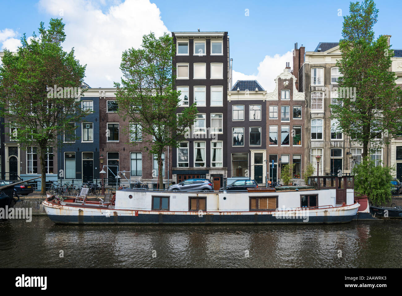 Netherlands, Amsterdam, Barge moored along edge of city canal with row ...