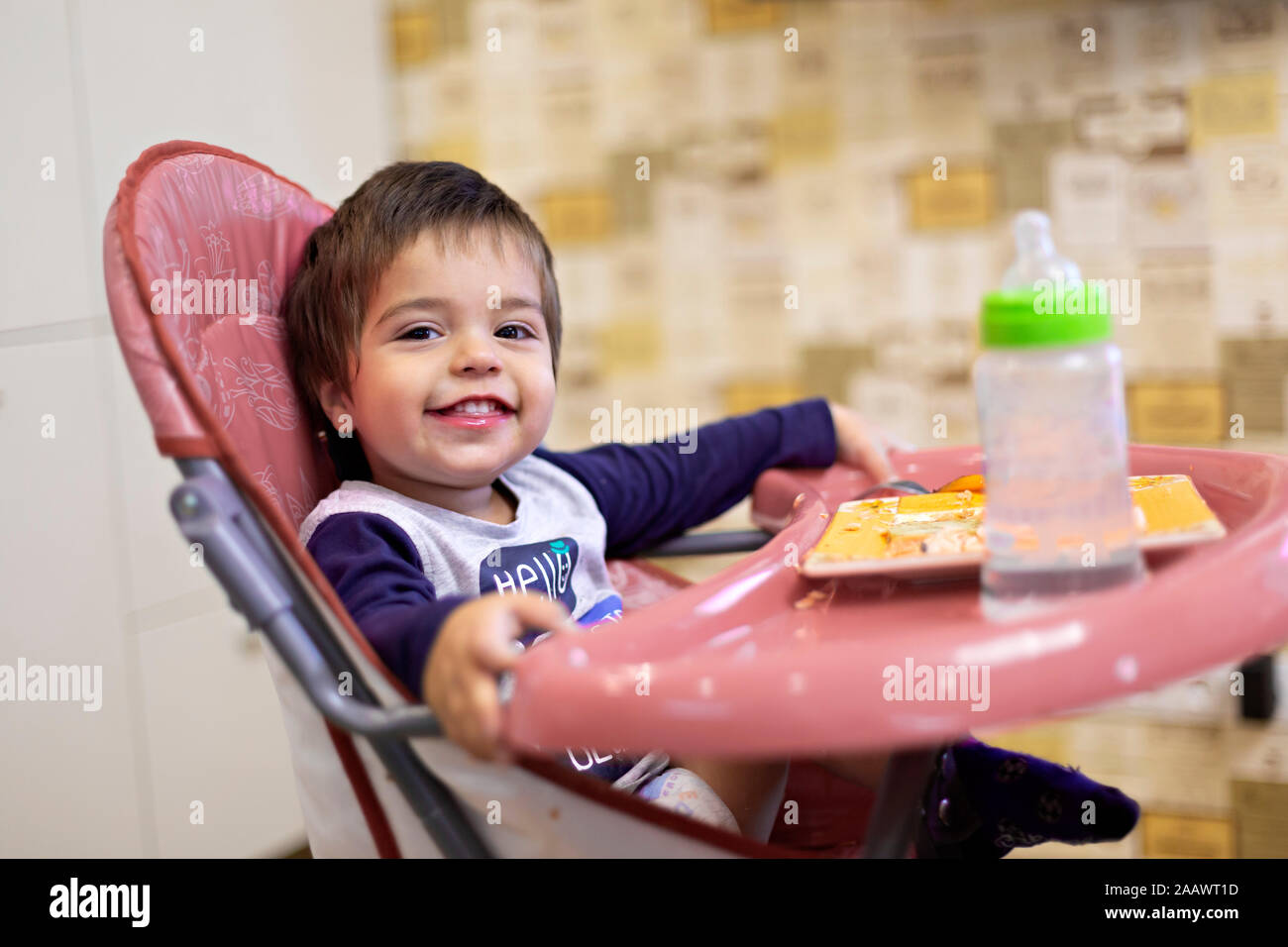 Portrait of happy little boy sitting on high chair Stock Photo - Alamy