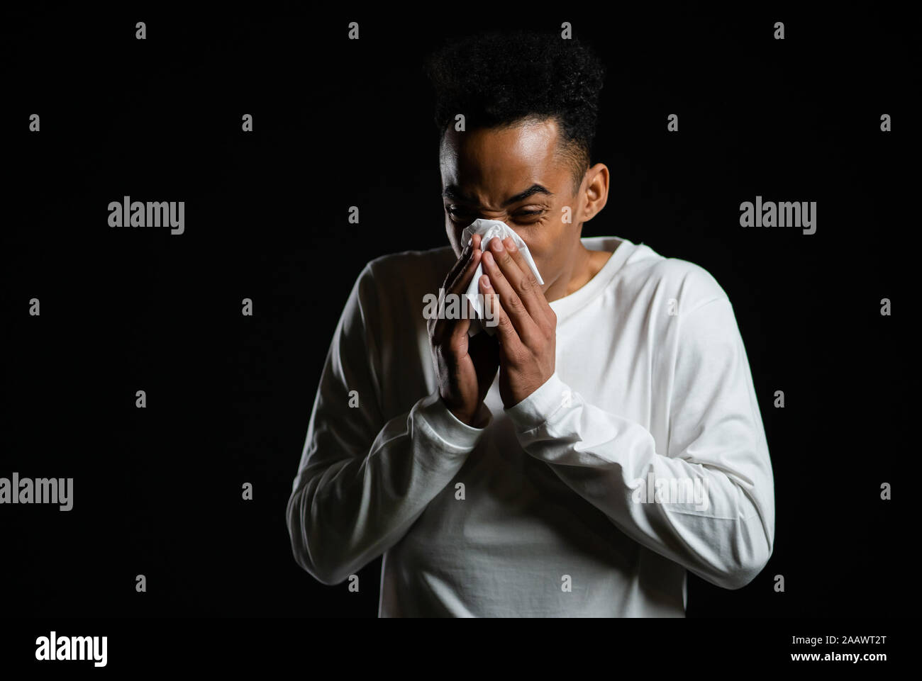 Young man sneezes into tissue.Man is sick, has cold or has allergic ...