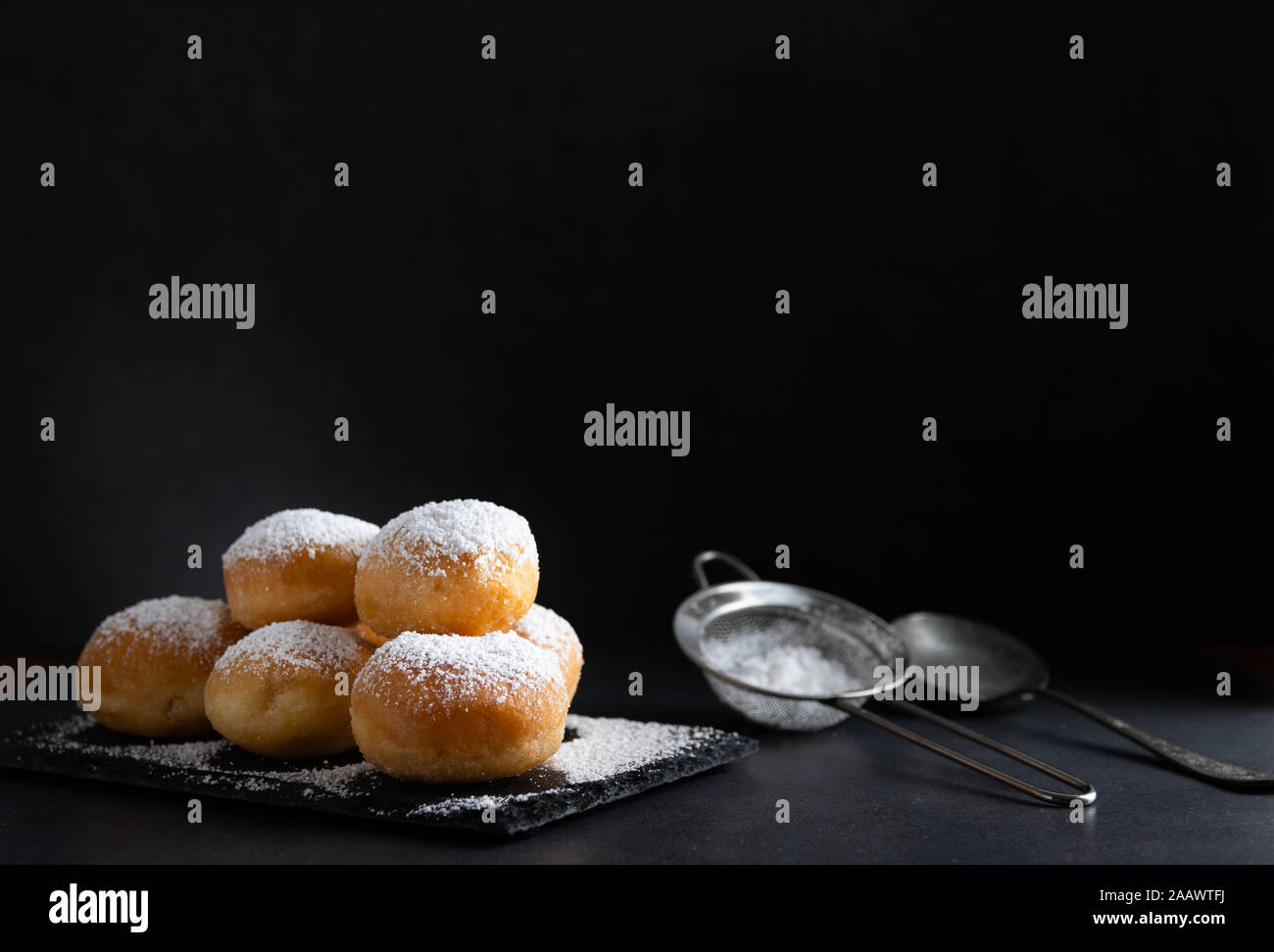 Homemade deep fried sweet fritters covered with sugar on a dark ...