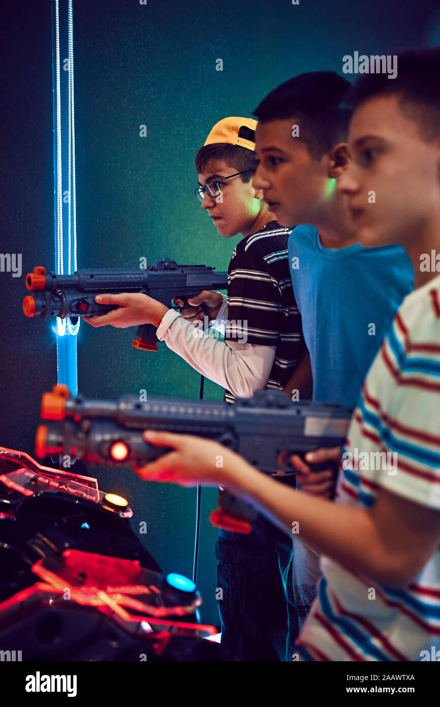 Teenage friends shooting with guns in an amusement arcade Stock Photo ...