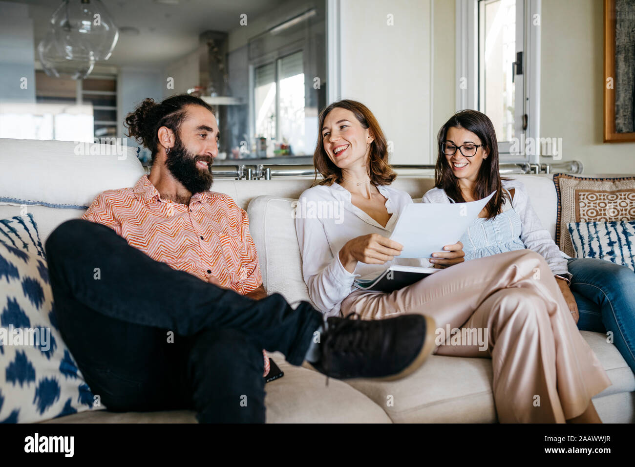Coworkers and friends sitting on couch with papers Stock Photo - Alamy