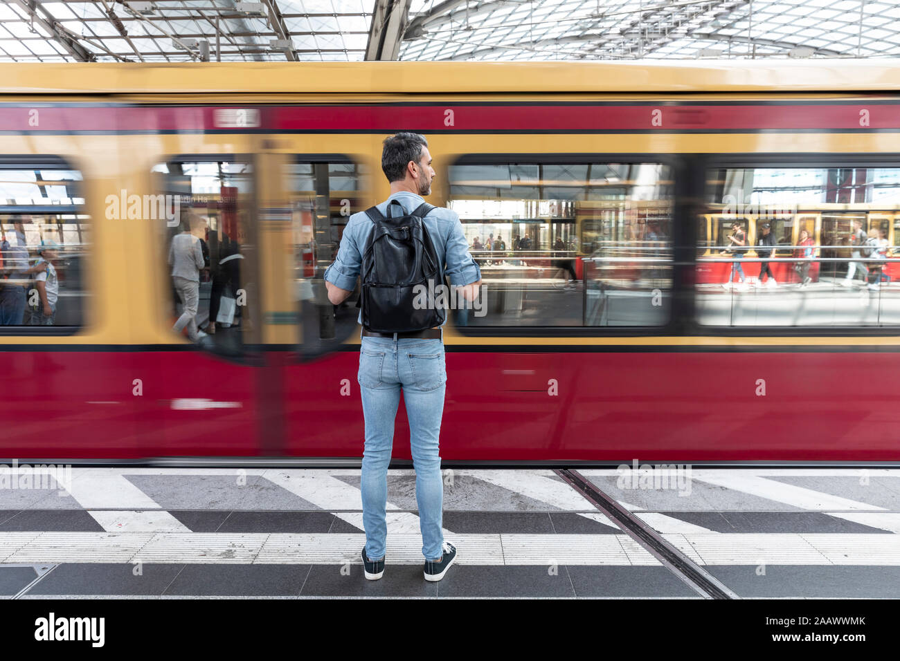 Rear view of man with backpack at the station platform while train ...