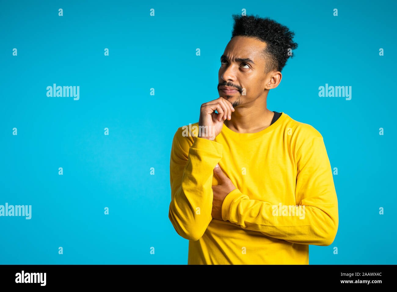 Thinking man looking up and around on blue background. Worried face ...