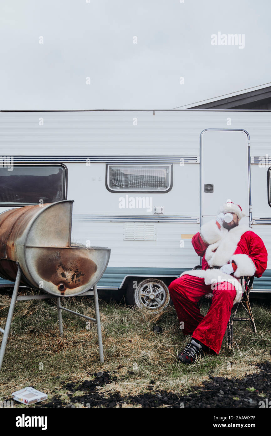 Santa claus preparing a barbecue in front of a camper Stock Photo - Alamy