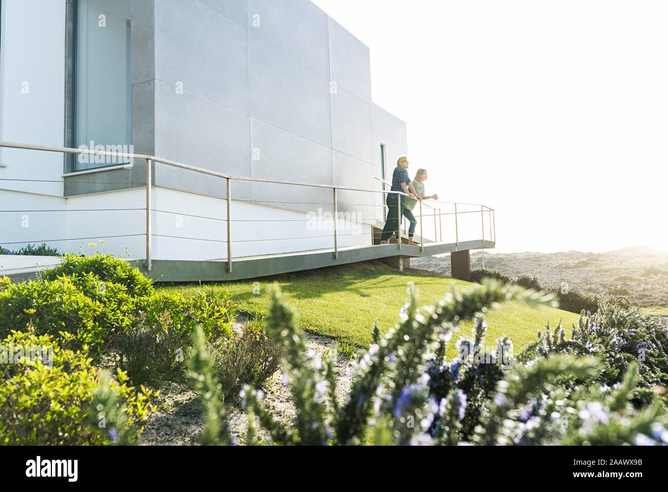 Couple standing in front of their modern home looking around Stock ...