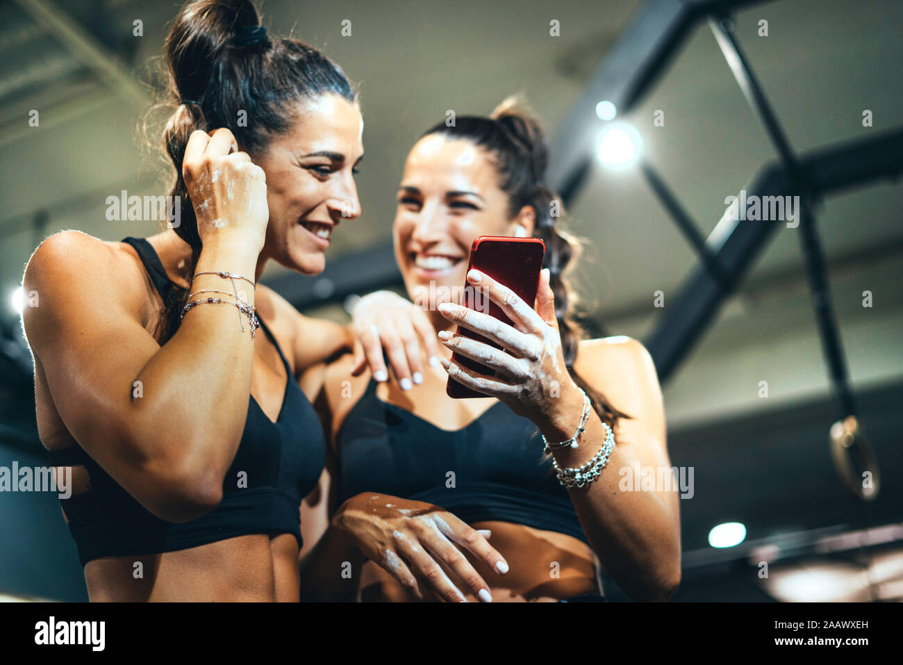 Smiling female twins in good shape using smartphone in a gym Stock ...