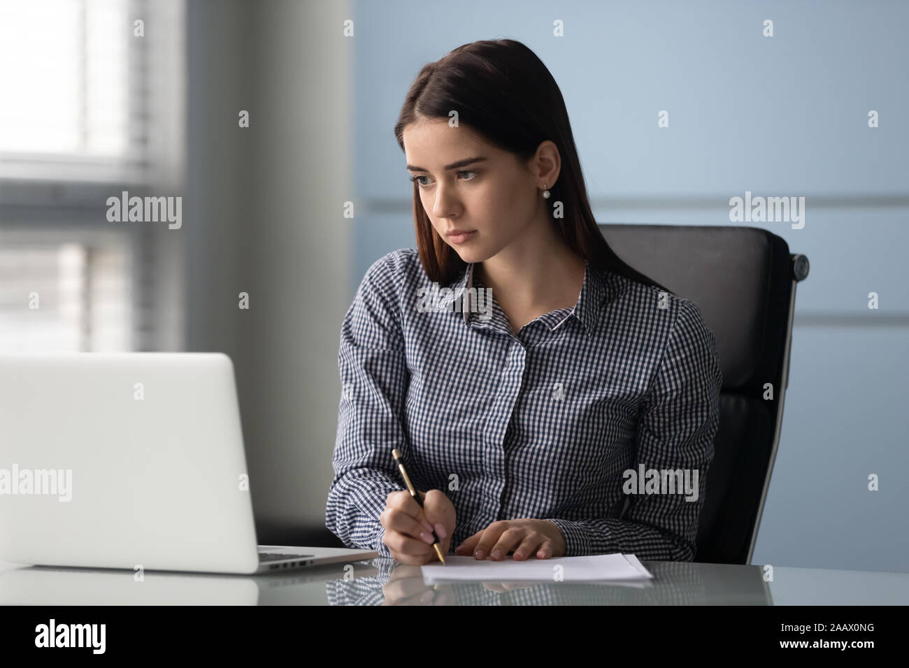 Concentrated female employee make notes working on laptop Stock Photo ...
