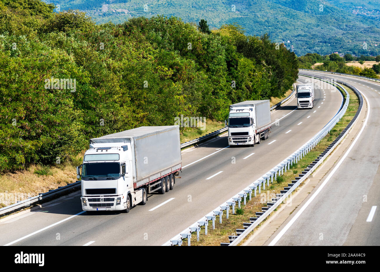 Three white Lorry trucks in line on a country highway under a beautiful ...