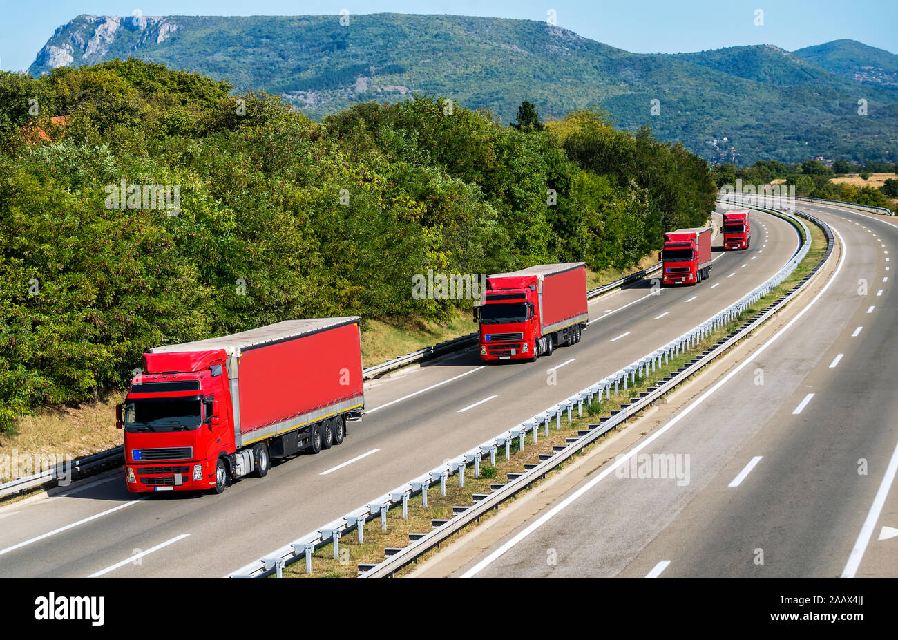 Caravan or convoy of Four red Lorry Lorry trucks in line on a country ...