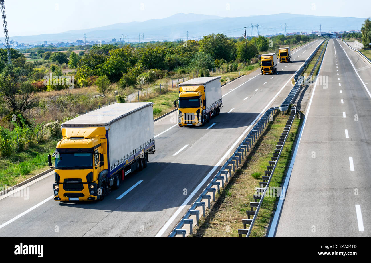 Caravan or convoy of Four yellow Lorry Lorry trucks in line on a ...