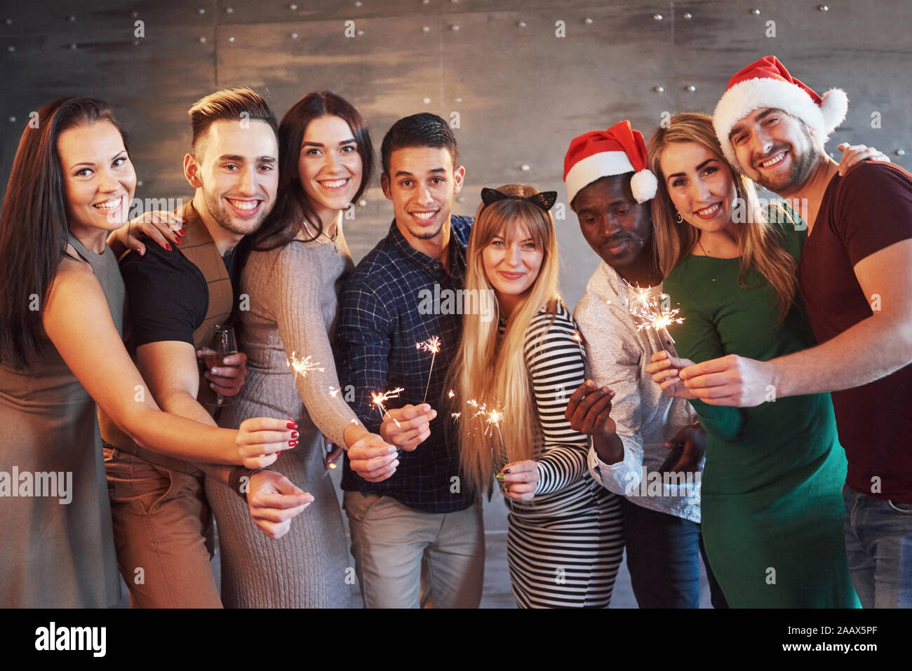 Party with friends. Group of cheerful young people carrying sparklers ...