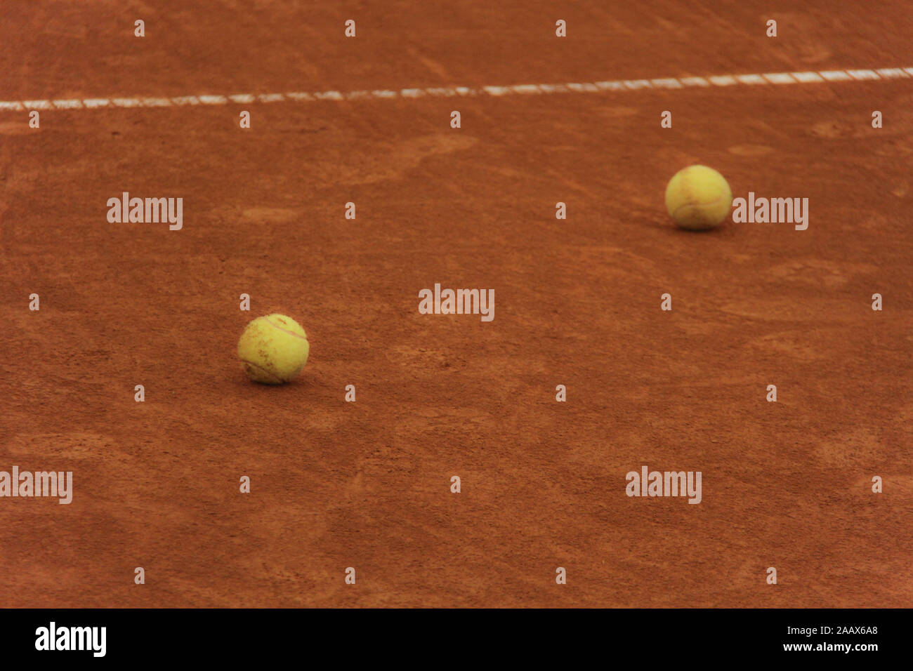 Tennis balls on red court with gray net Stock Photo - Alamy