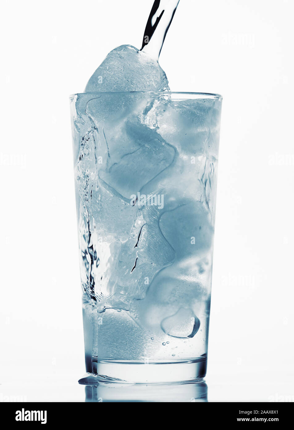 pouring water in a glass full of ice cubes, white background, blue ...