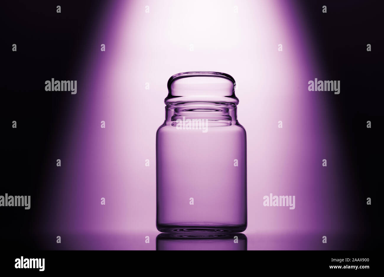 Empty glass jar on a magenta, black and white background with light ...
