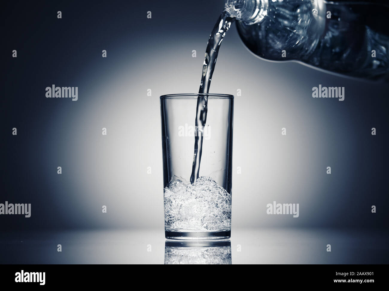 pouring sparkling water in a glass on a dark blue background Stock Photo - Alamy