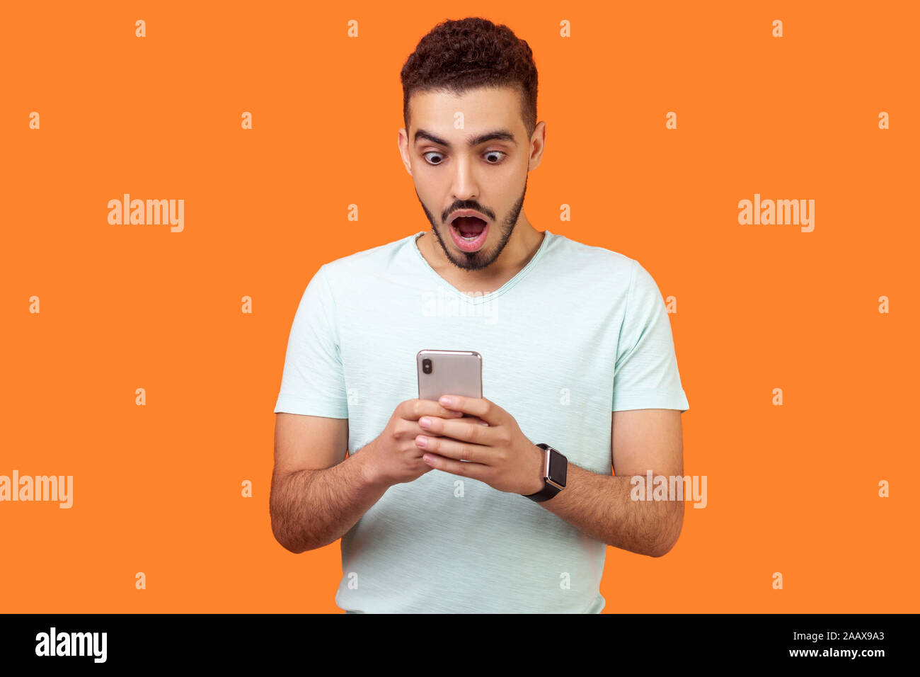 Portrait of young brunette man with beard in white t-shirt expressing ...