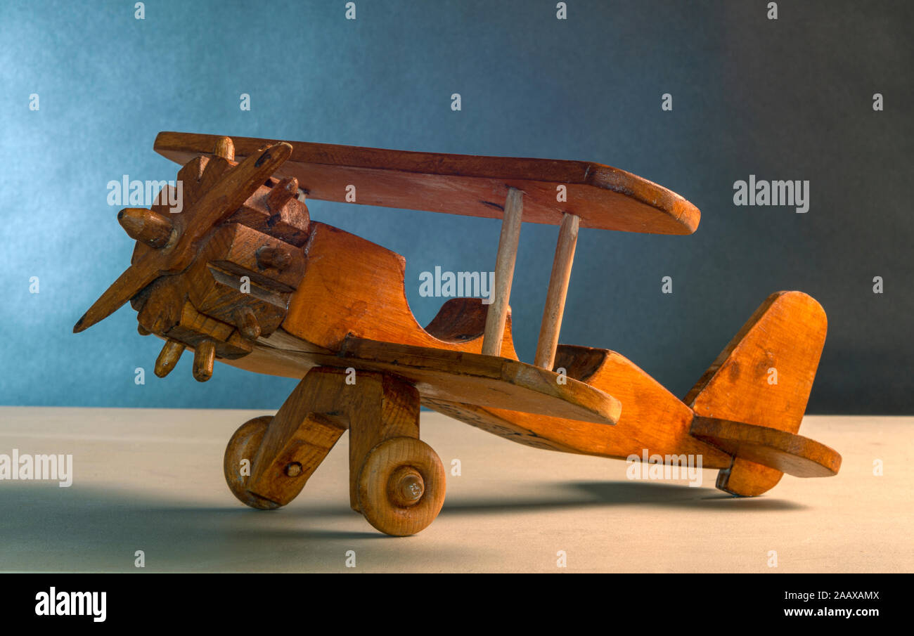 A wooden model biplane aircraft, in a studio setting shot against blue ...