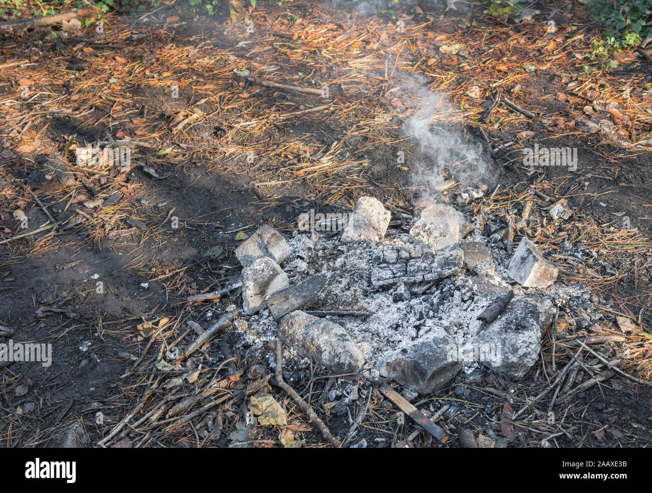 Smouldering wood ash remains from wood burning campfire set in a stone ...