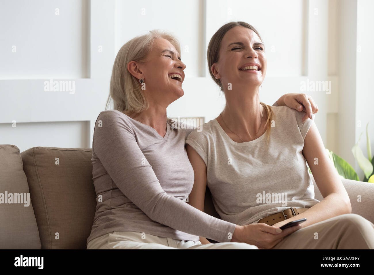 Overjoyed middle aged woman laughing at funny video with daughter Stock Photo - Alamy