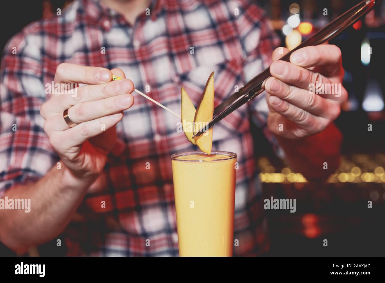 Bartender is decorating a cocktail with mango, toned image Stock Photo ...