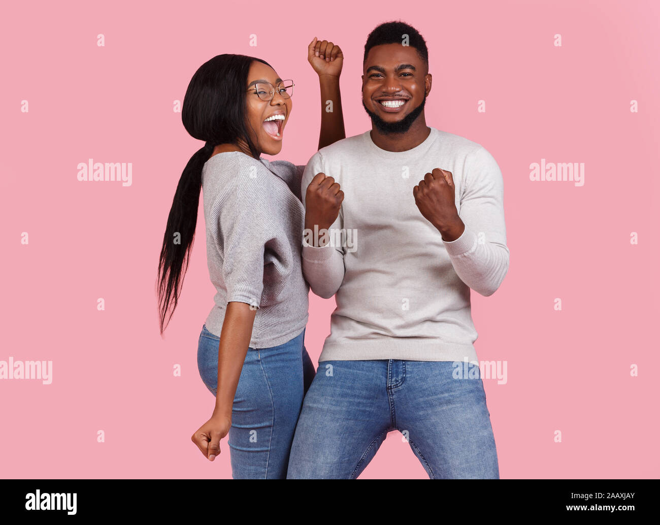 Successful couple celebrating win, dancing over pink background Stock ...