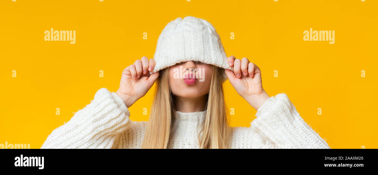 Blonde woman pulling down knitted white hat Stock Photo - Alamy